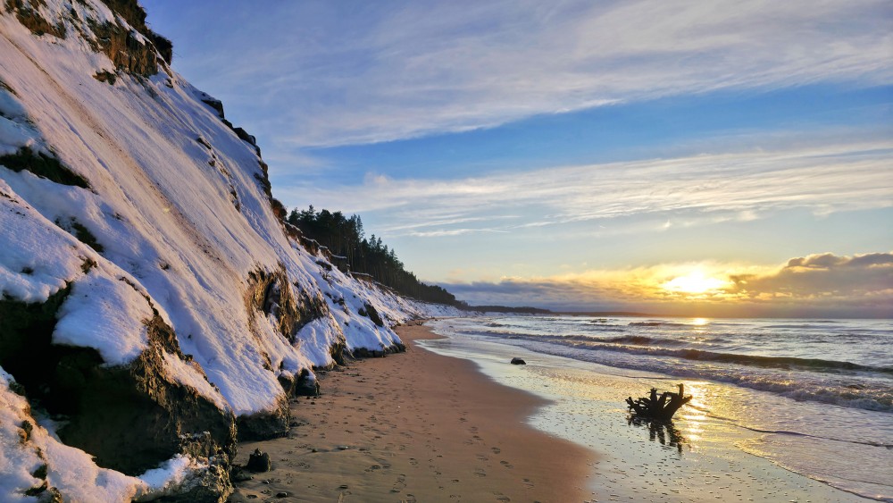Snowy Jurkalne steep bank by the sea with sandy beach and calm horizon ...