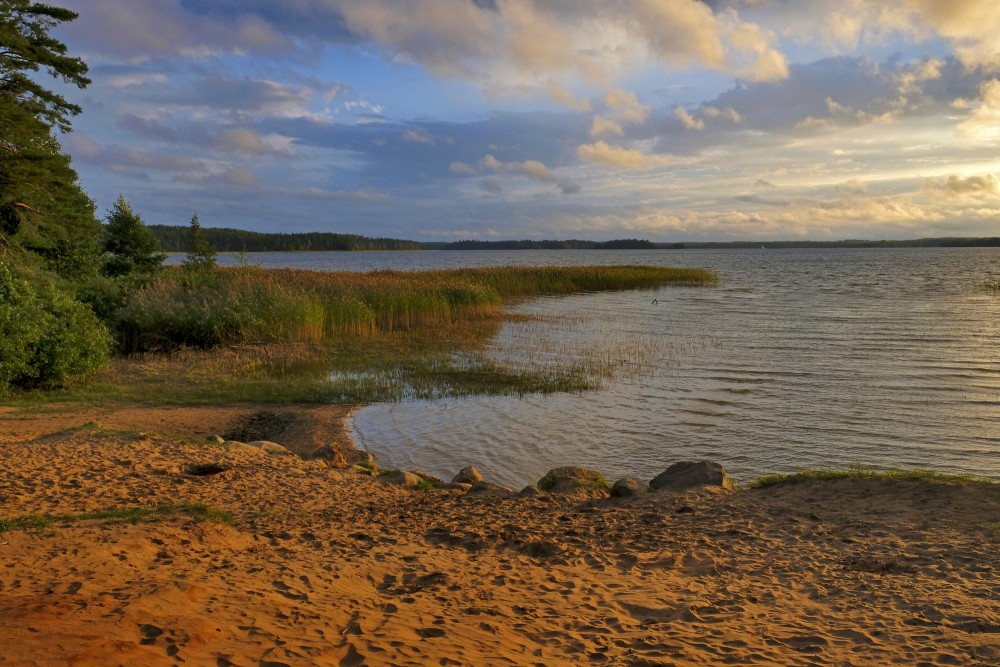 Sunset over a lake with golden reflection and dramatic cloud formations ...