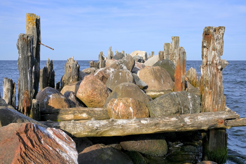 Old wooden jetty with stones and sea backdrop - redzet.lv
