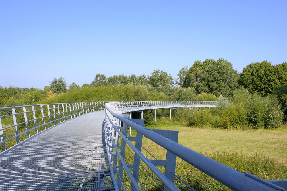 Pedestrian bridge over the Bārta in a green landscape at Vaclava Inta ...