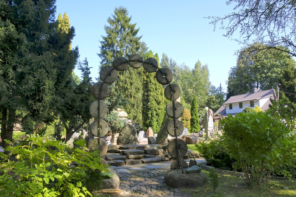 Stone garden gate with millstones and steps in a green park setting ...
